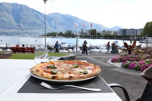 Uma pizza sobre a mesa, com vista para as montanhas ao fundo.