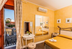 Quarto de hotel com cama, mesa de cabeceira, espelho, ar condicionado e vista para o exterior.