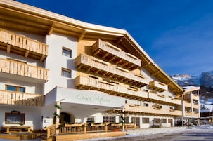 Hotel com várias andares, varandas de madeira e paisagem nevada ao fundo.
