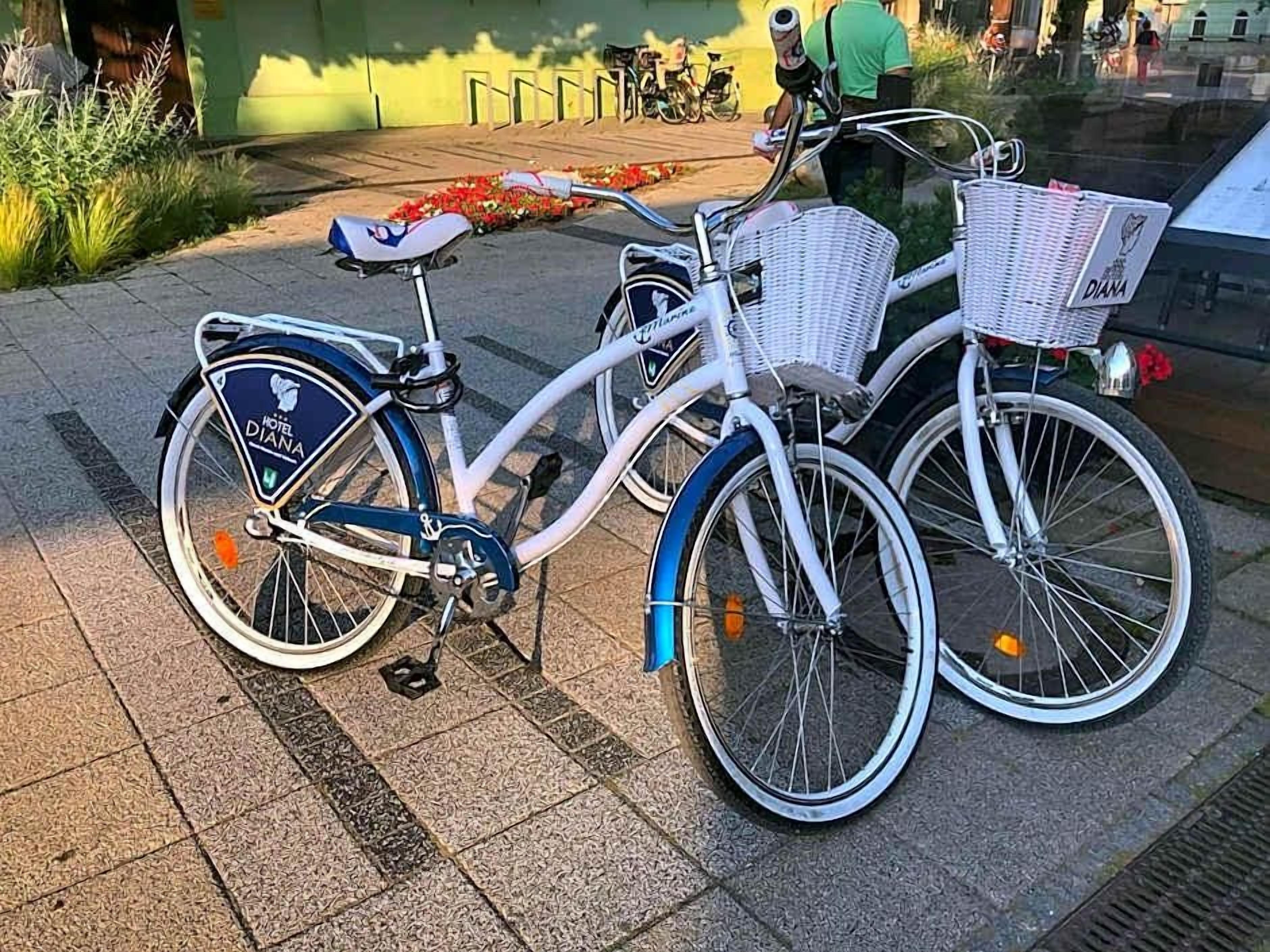 Uma bicicleta com cesta e bolsa de selim estacionada em superfície pavimentada.