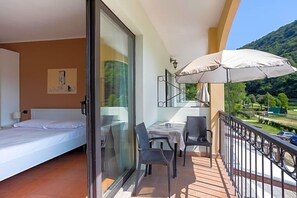 Uma varanda com mesa, cadeiras e um grande guarda-sol.