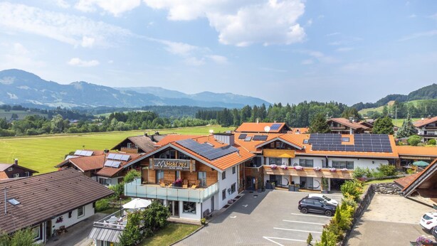 Hotel com vários edifícios, painéis solares e parque de estacionamento.