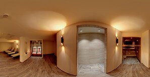 Interior moderno com corredor curvo, piso de madeira e área de estar com poltronas estofadas.