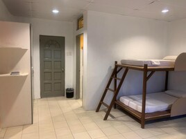 Uma cama beliche com escada, uma porta e uma lixeira em um quarto com piso revestido de azulejos.