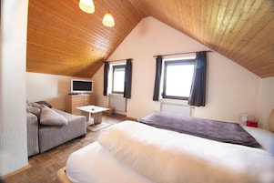 Um quarto aconchegante com uma cama, um sofá, uma mesinha e uma televisão.