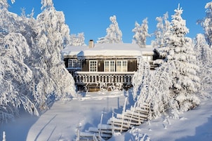 Uma casa de madeira rodeada por árvores cobertas de neve.