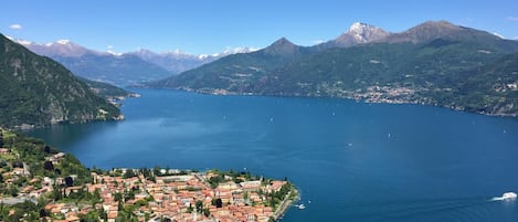 Uma cidade costeira com um porto de iates, rodeada por montanhas e um lago extenso.