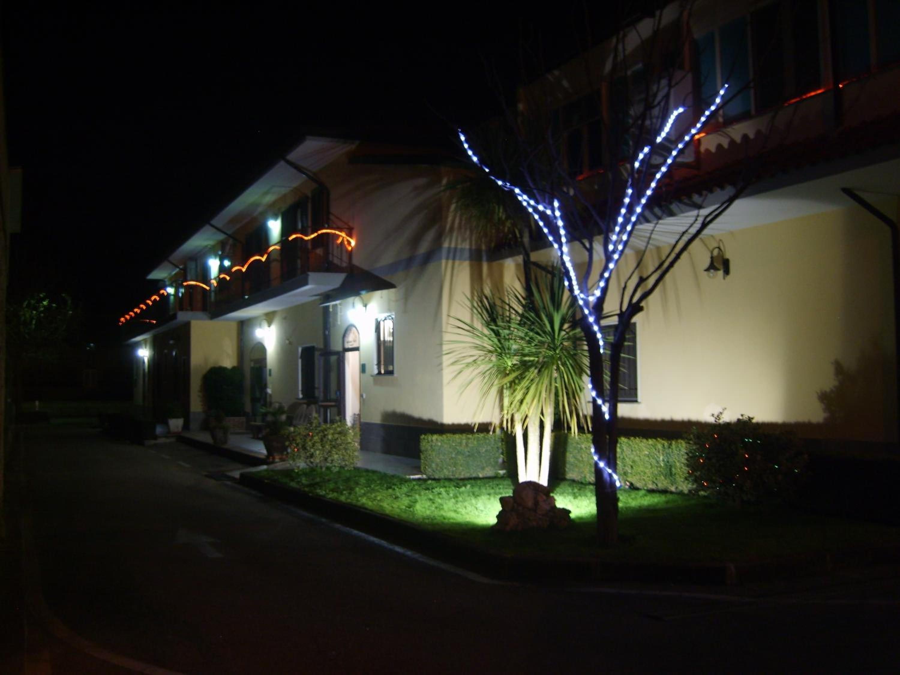 Edifício residencial com varanda, um pequeno jardim e luzes decorativas.
