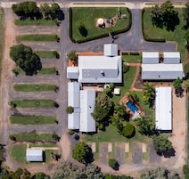 Vista aérea de um empreendimento com vários edifícios, piscina e áreas ajardinadas.