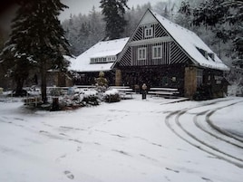 Um edifício coberto de neve com telhado inclinado, cercado por árvores carregadas de neve.