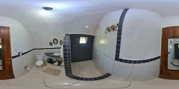 Casa de banho com design em azulejos brancos e pretos, sanita, lavatório e zona de duche.