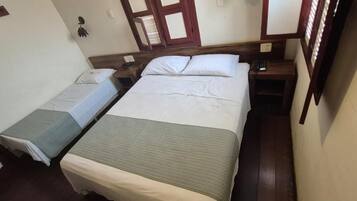 Quarto de hotel padrão com duas camas, uma mesinha de cabeceira e uma pequena mesa.