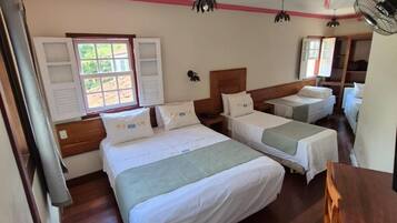 Quarto com duas camas, piso de madeira e janela com persianas.