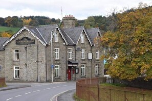Um edifício de pedra com uma placa que diz 'The Llanwedd Arms Hotel & Restaurant'.