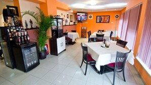 Um restaurante com área de bar, várias mesas e cadeiras.