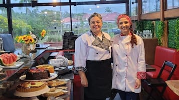 Duas pessoas em um restaurante, com diversas sobremesas expostas.