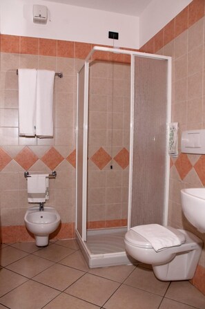 Casa de banho com chuveiro, sanita, bidé e lavatório.
