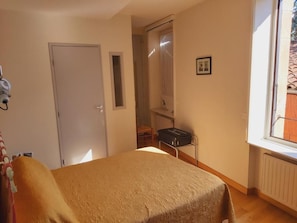 Um quarto com cama, guarda-roupa, radiador e janela.