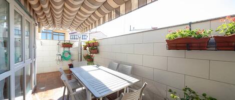 Um pátio com mesa e cadeiras, um jardim suspenso e piso de azulejos.