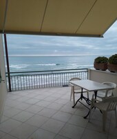 Varanda com vista para o oceano, uma mesa branca e duas cadeiras.