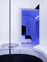 Um interior moderno com uma plataforma circular, um sofá branco e uma televisão.