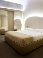 Quarto de hotel moderno com cama grande, espelho e vista do céu.
