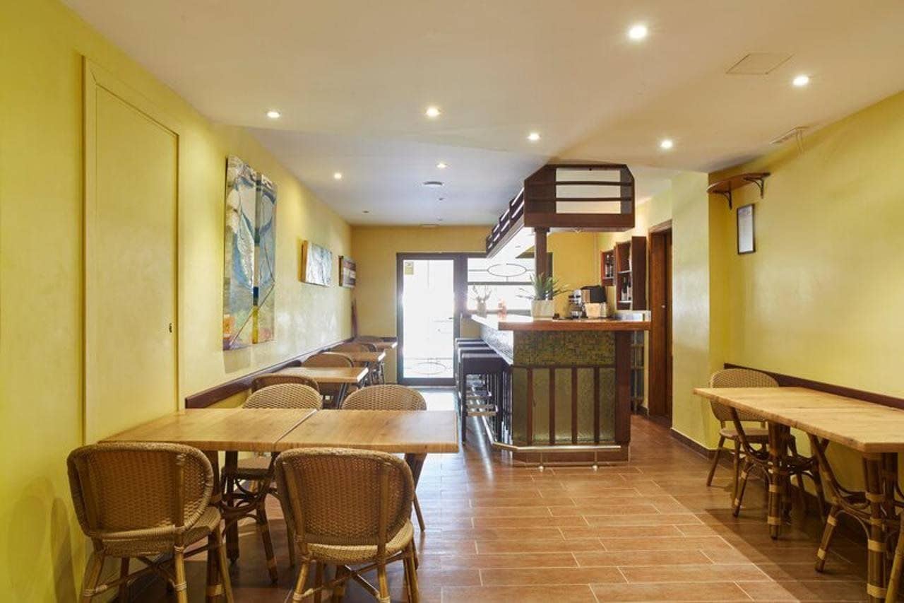 Interior de restaurante com pé-direito alto, balcão central e várias áreas de estar.