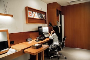 Um espaço de escritório moderno com uma mesa de madeira, um laptop, um computador de mesa e uma estante com obras de arte emolduradas.