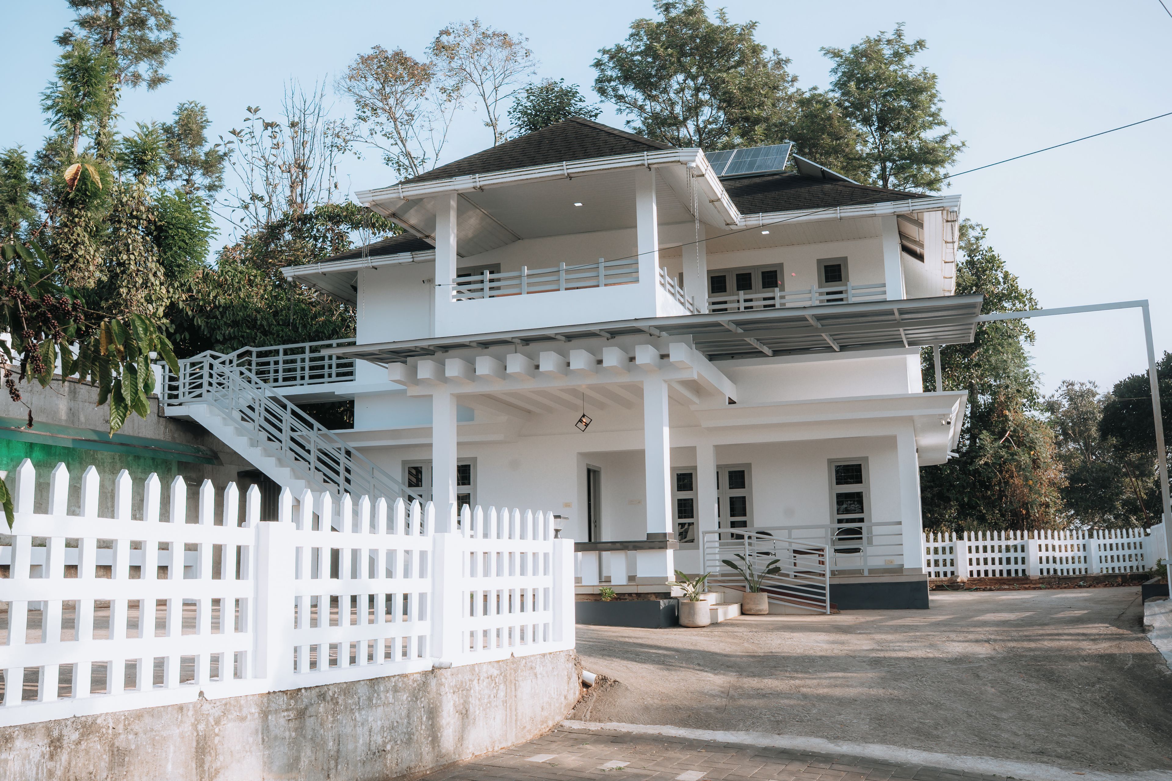 Um edifício de dois andares com varanda e cerca branca de piquete.