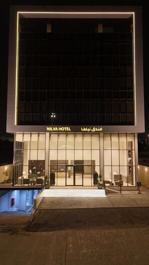 Um hotel moderno com entrada imponente e sinalização iluminada.