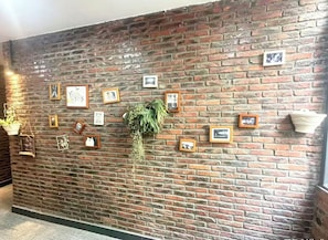 Pared de tijolos com quadros emoldurados e planta pendurada.