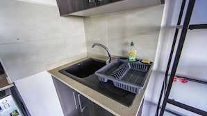 Cozinha compacta com pia, escorredor de louça e uma garrafa de detergente.