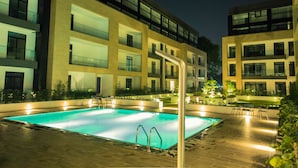 Área de piscina com um edifício moderno ao fundo.