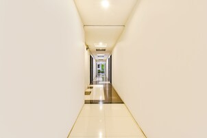 Um corredor comprido e estreito com piso espelhado e paredes brancas.