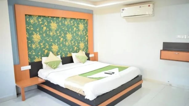 Quarto com cama, mesa de cabeceira, ar-condicionado fixado na parede e estante embutida.