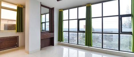Quarto de hotel com uma grande janela, uma TV de tela plana e um armário de madeira.