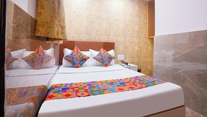 Quarto de hotel com cama, travesseiros, mesa de cabeceira e parede com um padrão de letras.
