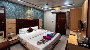 Quarto de hotel com cama, mesa de cabeceira, guarda-roupa e ventoinha no teto.