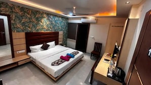 Quarto de hotel moderno com uma cama grande, uma escrivaninha com cafeteira e um ventilador de teto.