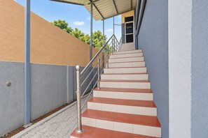 Escadaria com corrimão de metal que leva à entrada de um edifício.