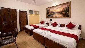 Quarto de hotel com duas camas, uma escrivaninha, uma cadeira e um quadro na parede.