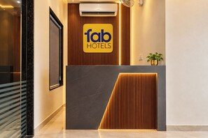 Uma área de recepção com uma placa 'fab hotels', design em painel de madeira e piso de mármore.