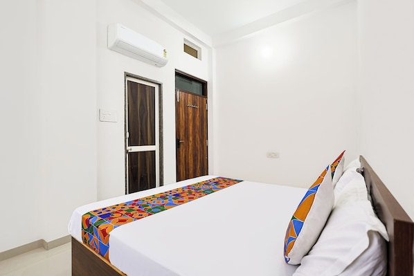 Quarto com cama, guarda-roupa e ar condicionado.