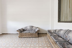 Quarto de canto com piso estampado, um sofá e uma poltrona.