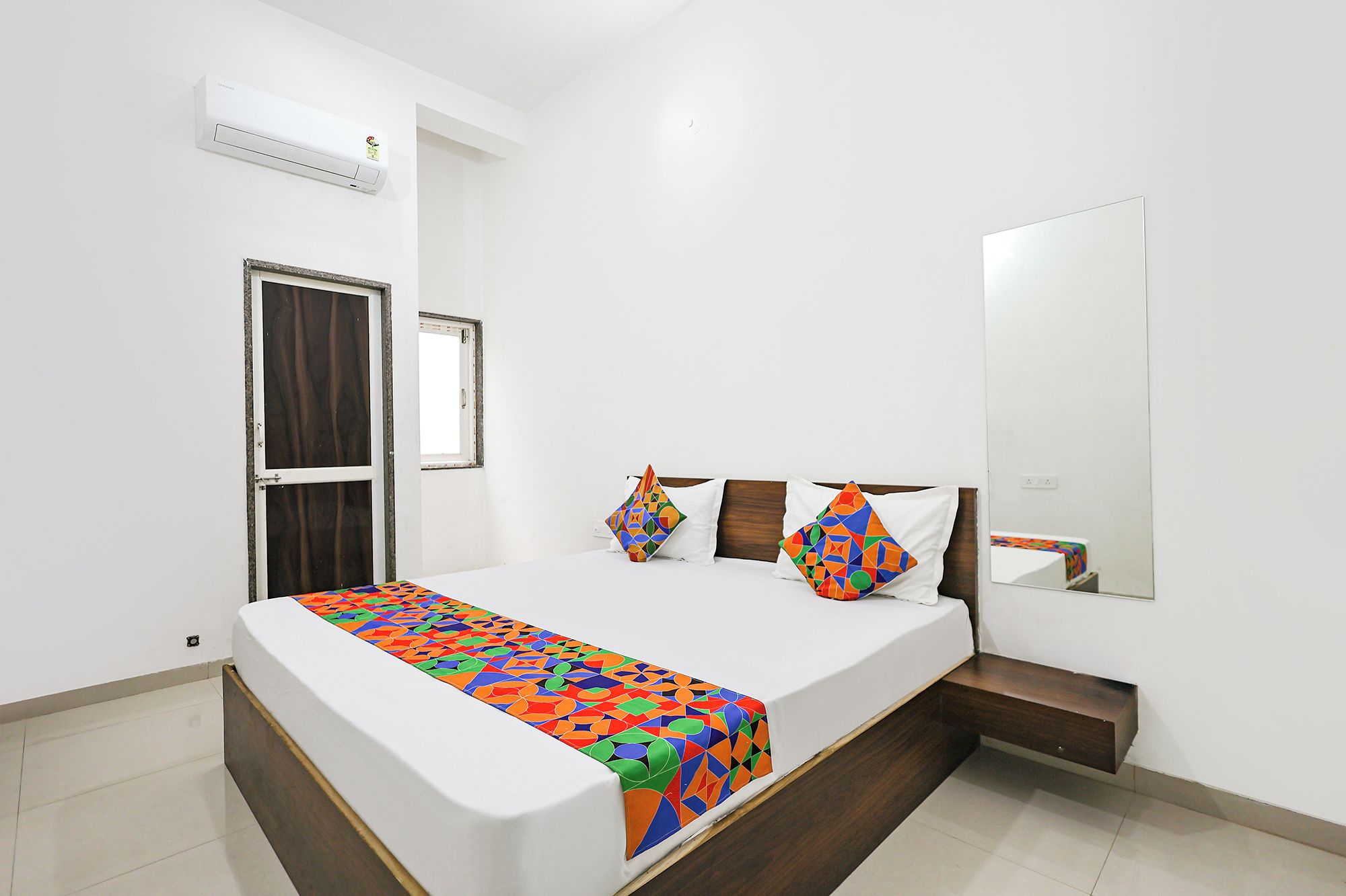 Quarto com cama, janela, espelho e estante embutida.