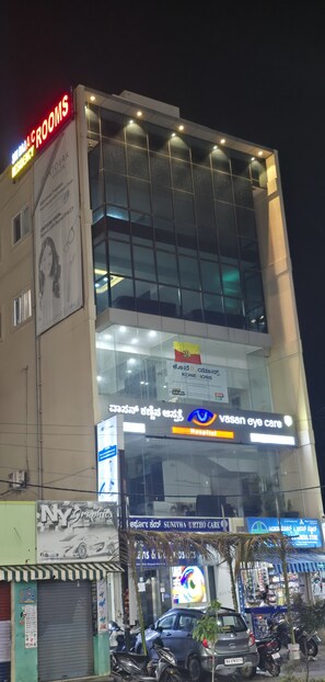 Um edifício de vários andares com sinalização para 'KONTOURA VISION' e 'Vasan Eye Care' no nível térreo.