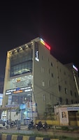 Um edifício de vários andares com uma placa grande exibindo 'Sri Raj Residency Rooms' no topo.