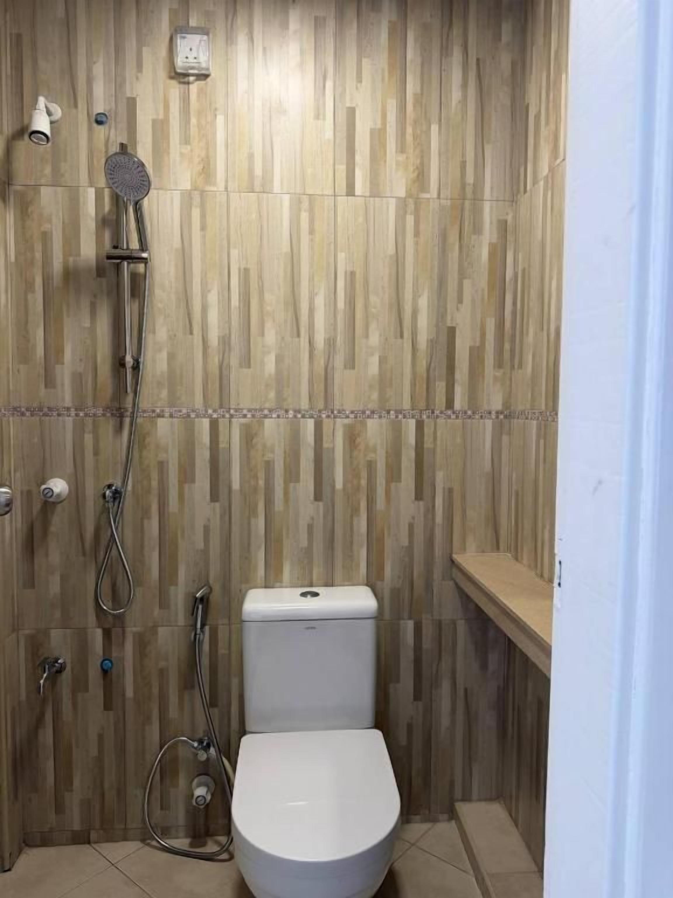 Casa de banho pequena com sanita, chuveiro e lavatório.