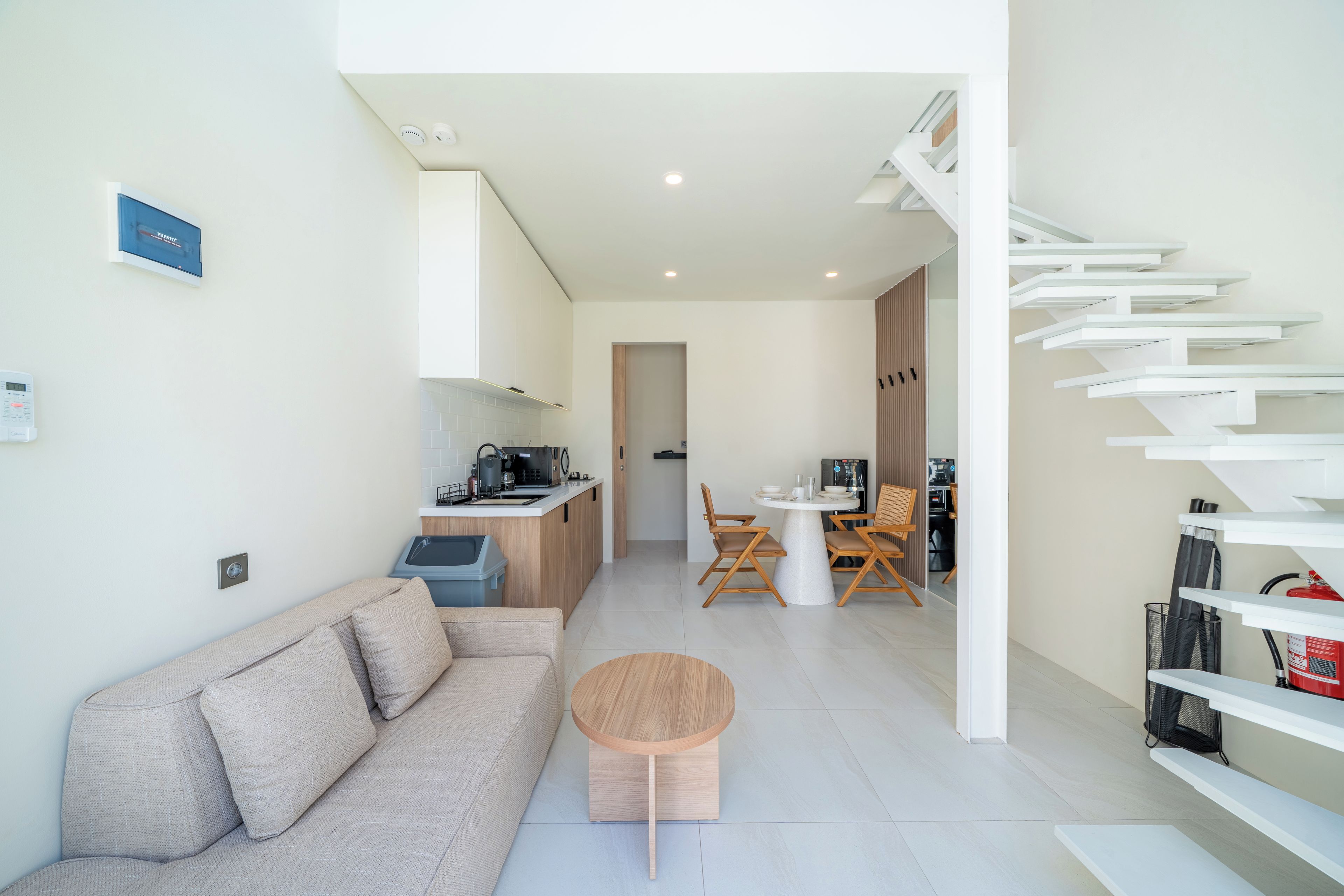 Um apartamento moderno com sala de estar, cozinha, área de refeições e escada.