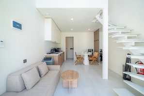 Um apartamento moderno com sala de estar, cozinha, área de refeições e escada.